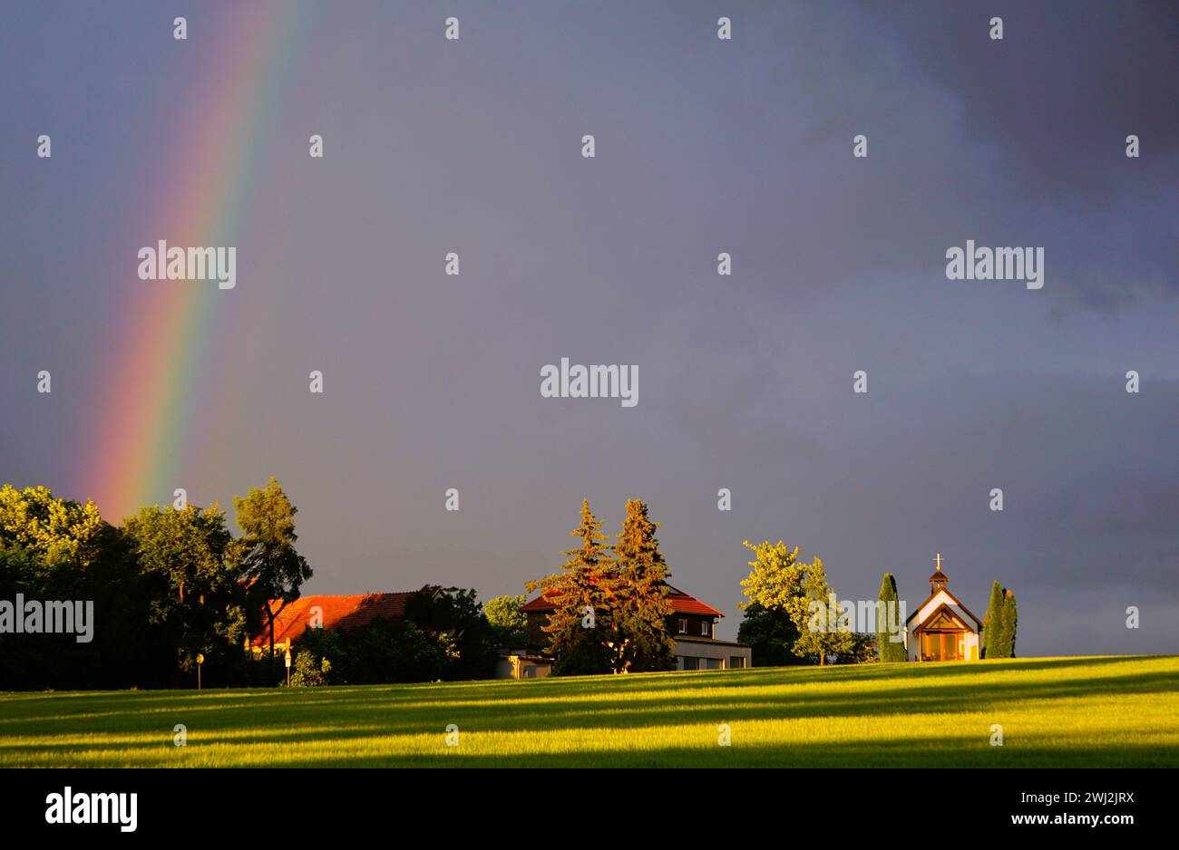 Sky and rainbow over a field with nearby trees Stock Photo - Alamy