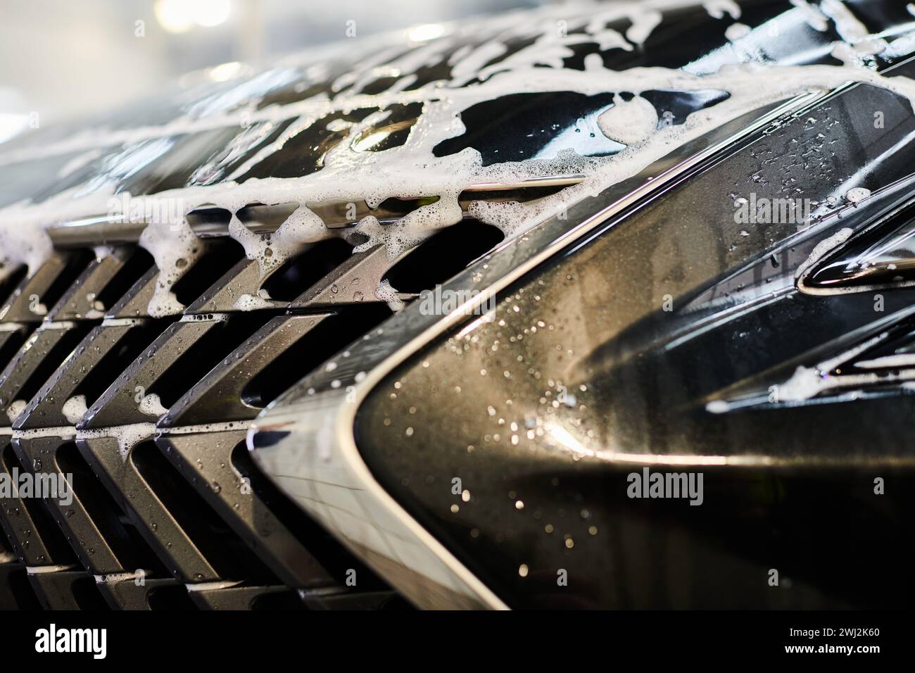object photo of shiny bumper of black modern car covered with soap ...