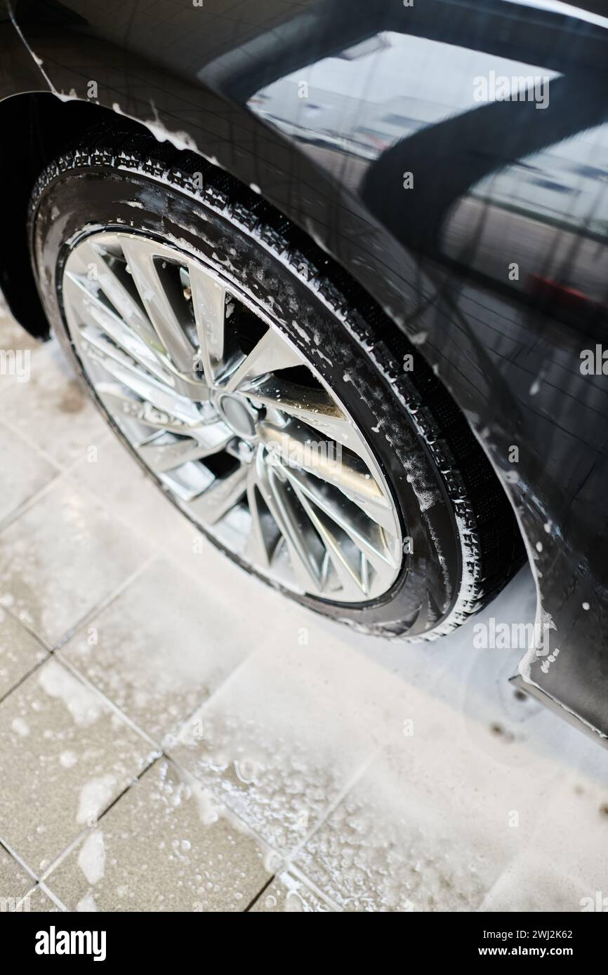 object photo of shiny tires of black modern car covered with soap ...