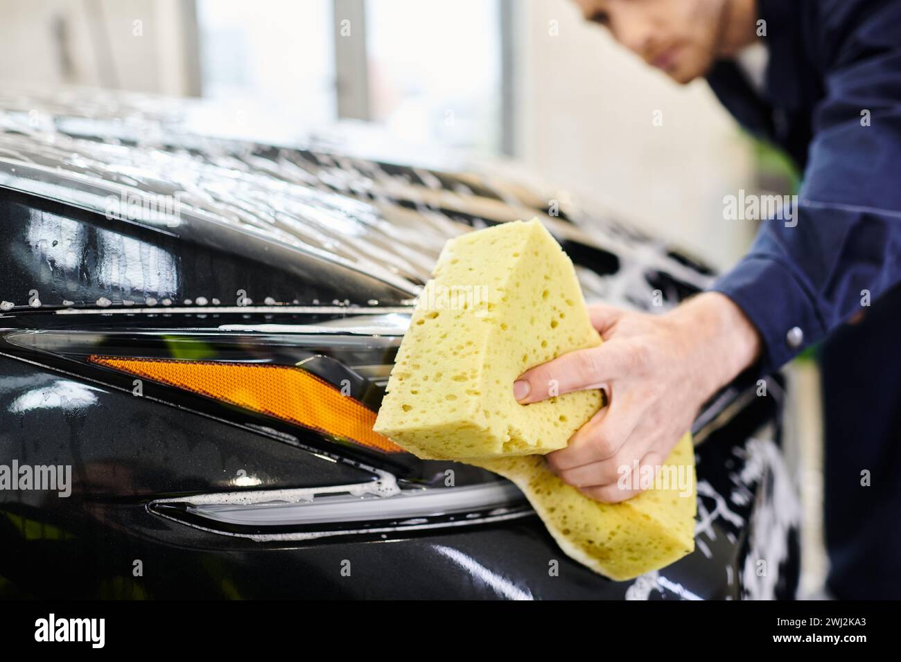 focus on soapy yellow sponge in hands of blurred attractive serviceman ...