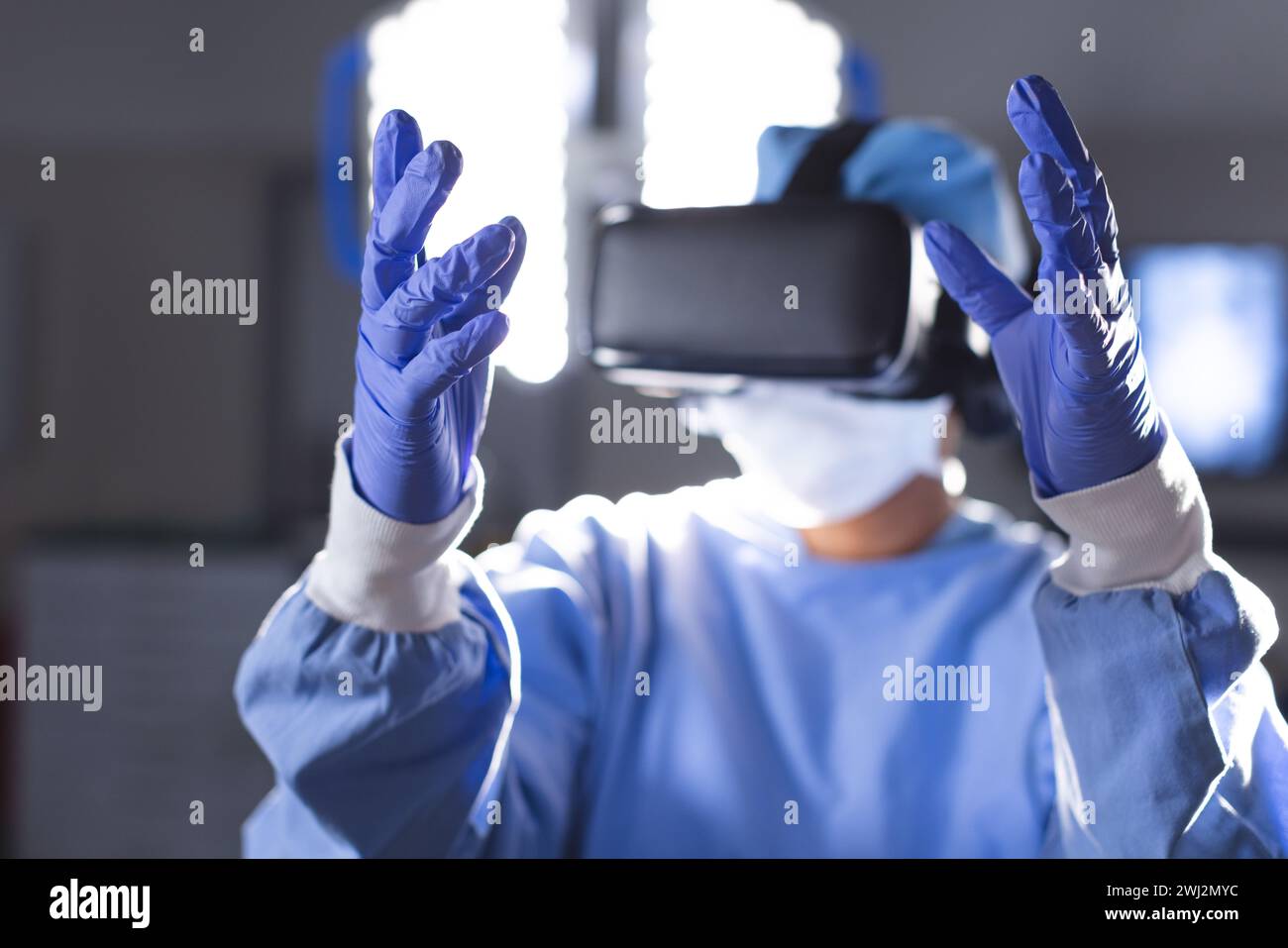 Biracial female surgeon wearing surgical gown using vr headset in ...