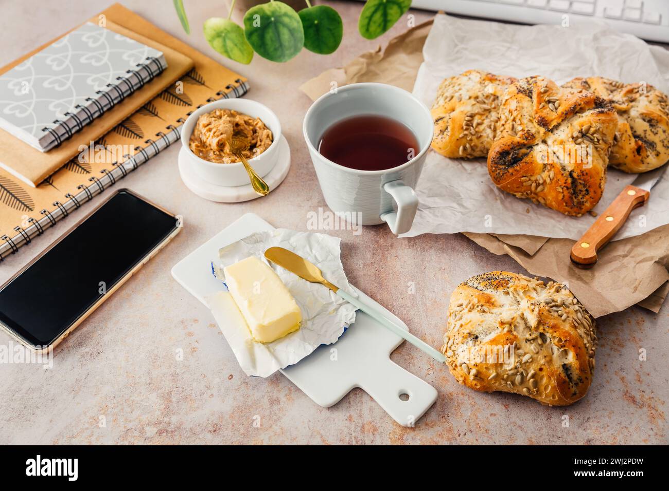Breakfast at office workplace, fresh bread rolls with butter and cup of ...