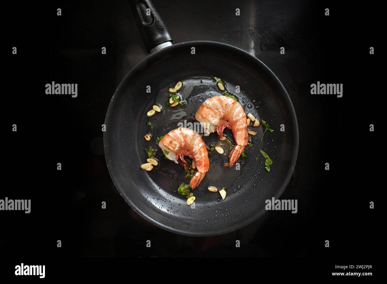 Frying jumbo tiger prawns in olive oil with garlic and herbs in a pan ...