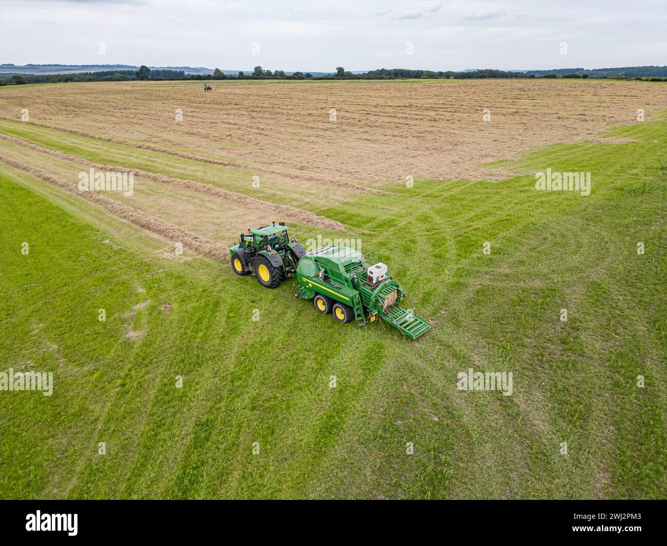 UK farming. Aerial drone photography of John Deere tractor haymaking in ...