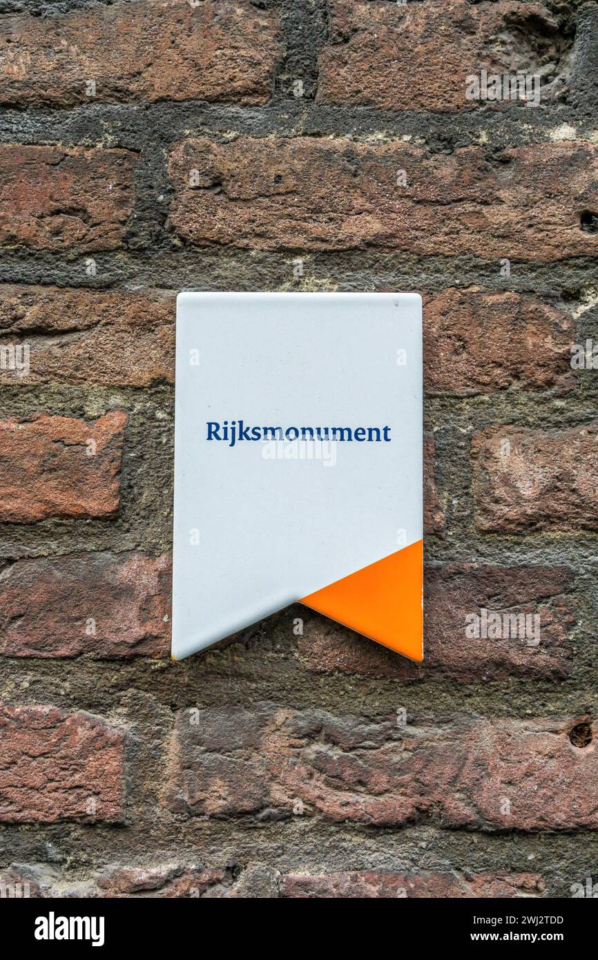 A white sign with an orange highlight on a brick wall indicating in ...