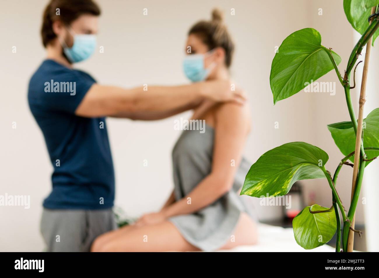 Man manual therapist wearing prevention mask is working with a woman ...