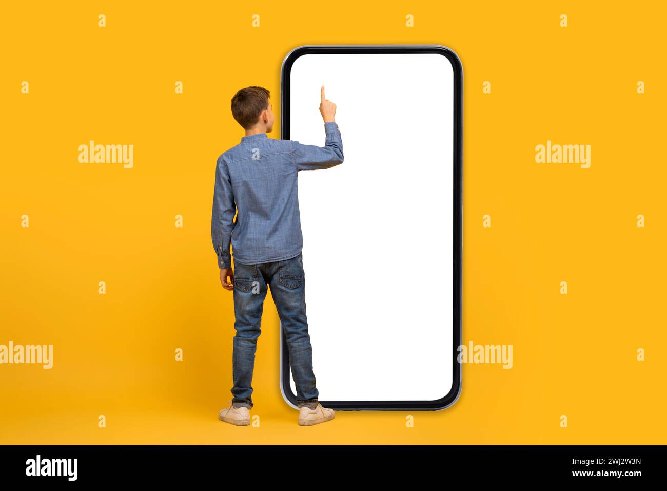Teenage boy standing and pointing at huge smartphone screen with white ...