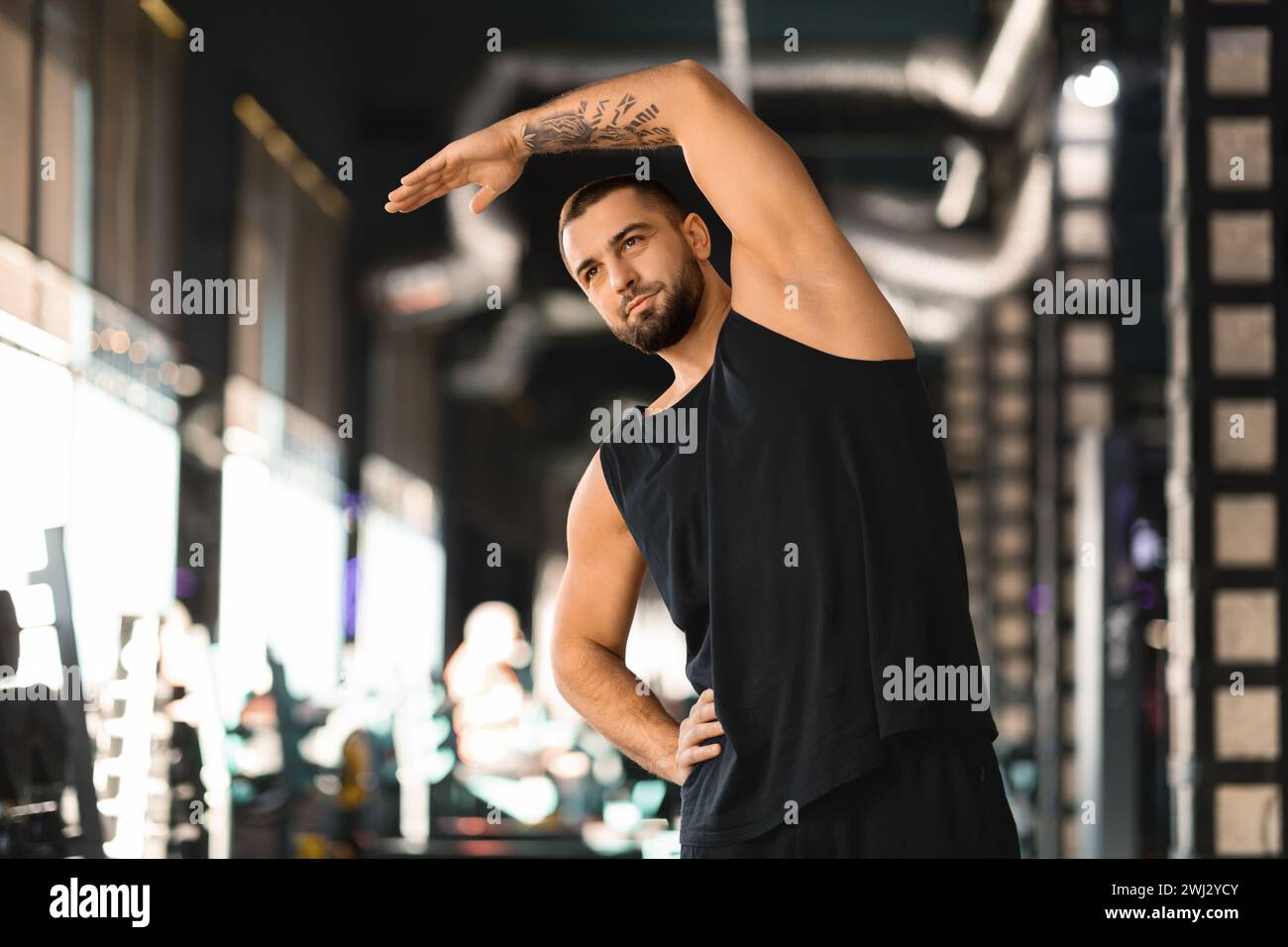 Handsome muscular man stretching his muscles before workout at modern ...