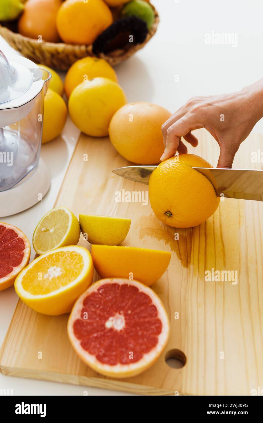 Female hands with knife cutting citrus fruits for homemade fresh juice ...