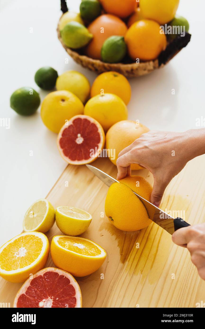 Female hands with knife slicing citrus fruits on cutting board for ...