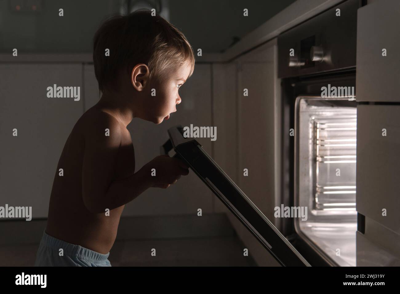 Curious baby boy opens the hot oven. Concept of safety and possible ...