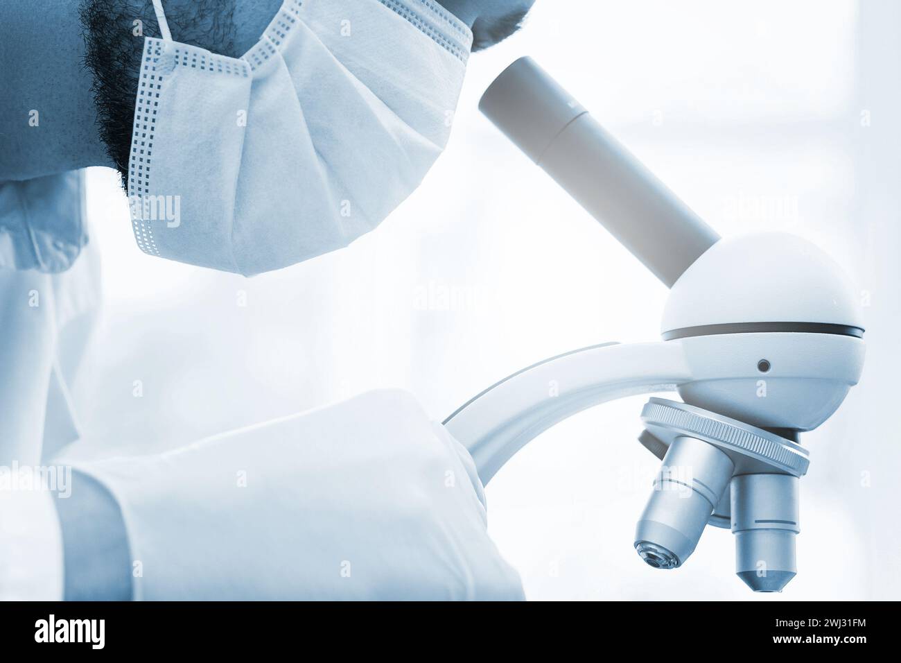 Scientist wearing medical mask is using microscope in a laboratory ...