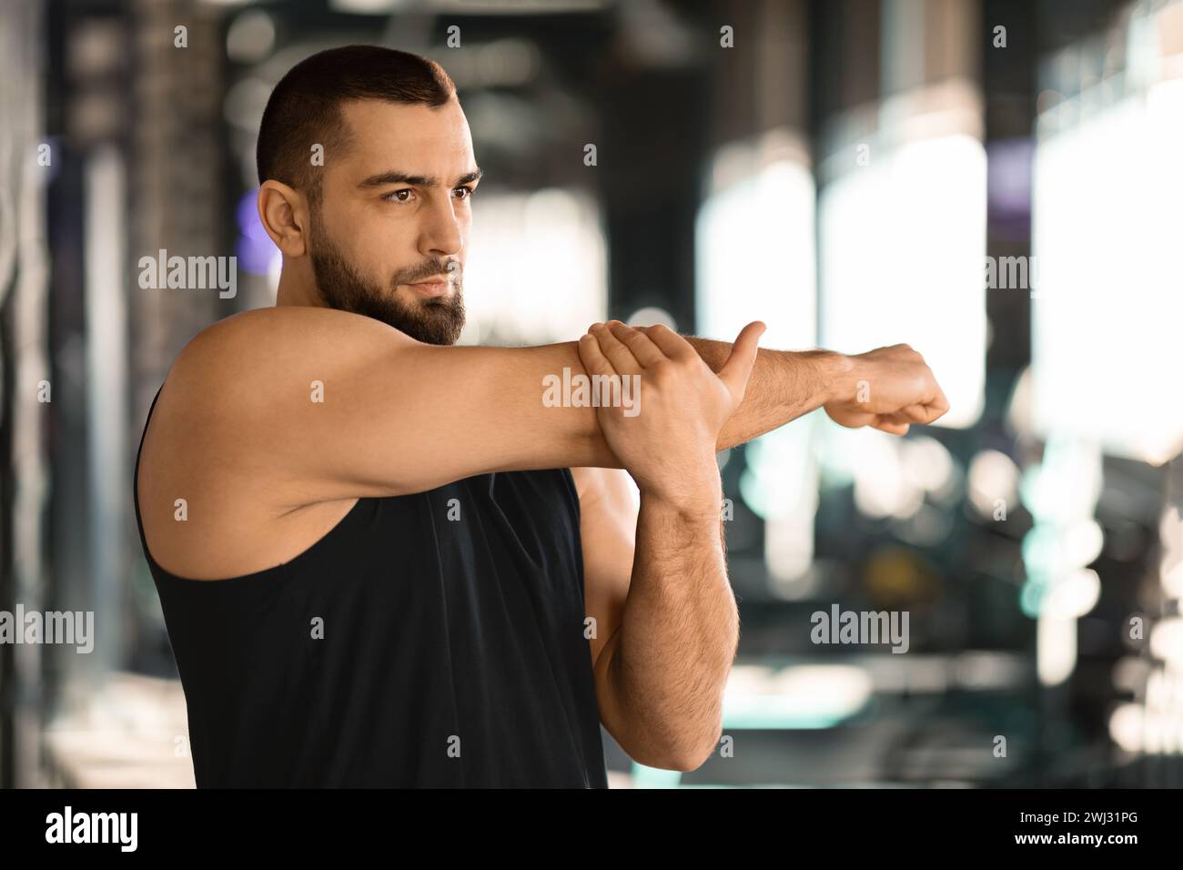 Portrait Of Athletic Young Man Stretching Arm Muscles At Gym Stock ...