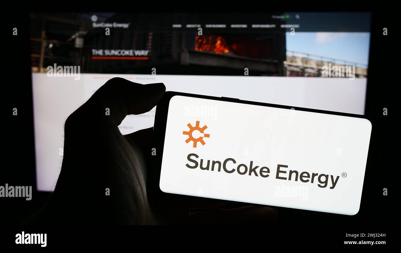 Person holding cellphone with logo of US coke producing company SunCoke ...