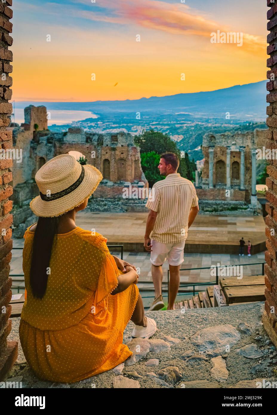 Taormina Sicily, couple watching sunset at the Ruins of the Ancient Greek Theater Taormina ...