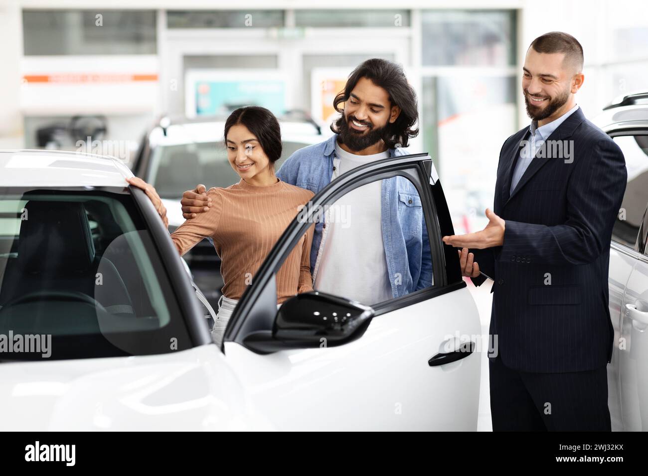 Young indian loving couple choosing car at luxury auto dealership Stock ...