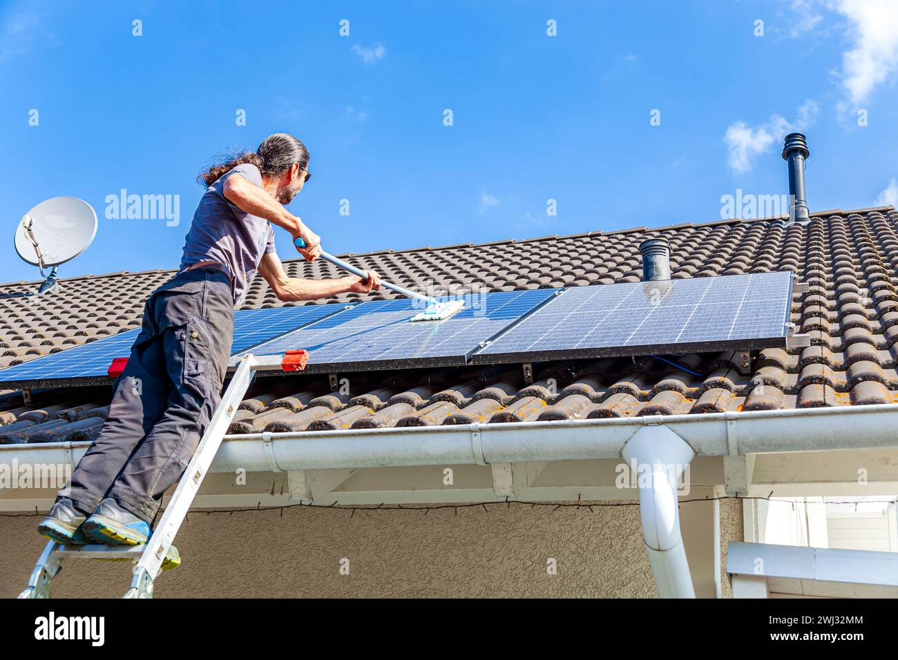 Man holding mop cleaning solar panels. cleaning of solar modules with ...