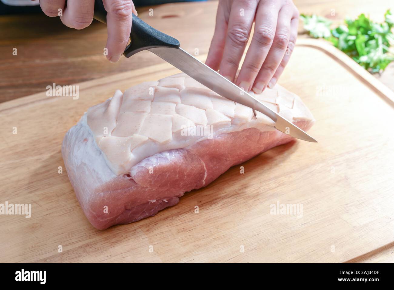 Rind from a raw roast pork is incised in a diamond shape with a sharp ...