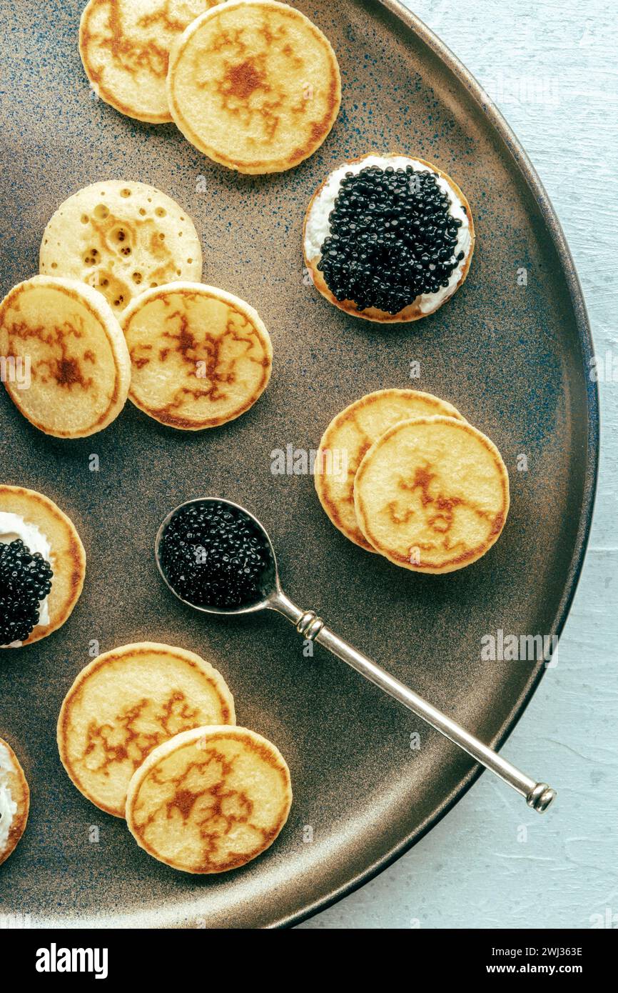 Blinis with black caviar and cream cheese, shot from above on a festive ...
