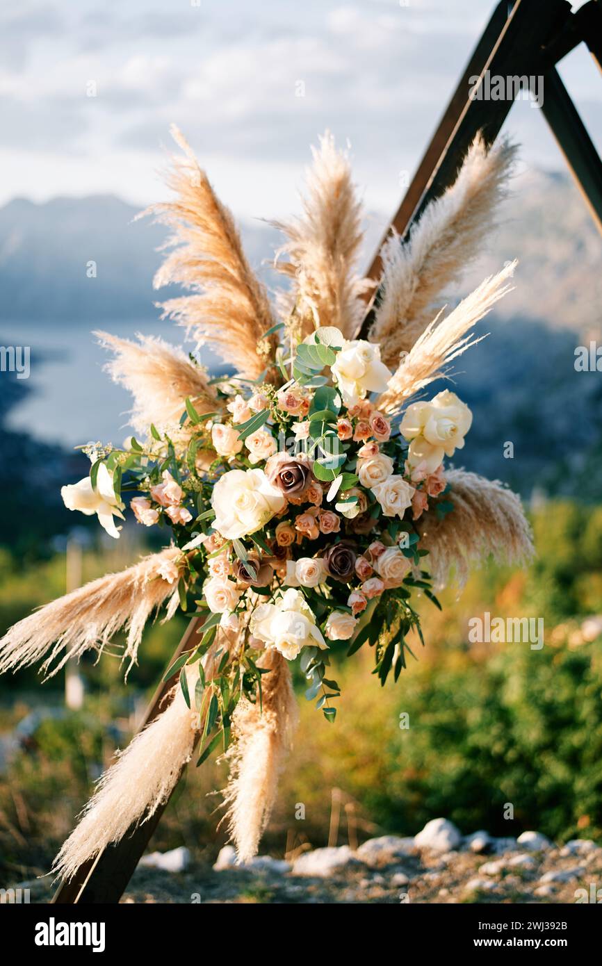 Colorful bouquet on the stand of a wedding triangular arch standing in ...