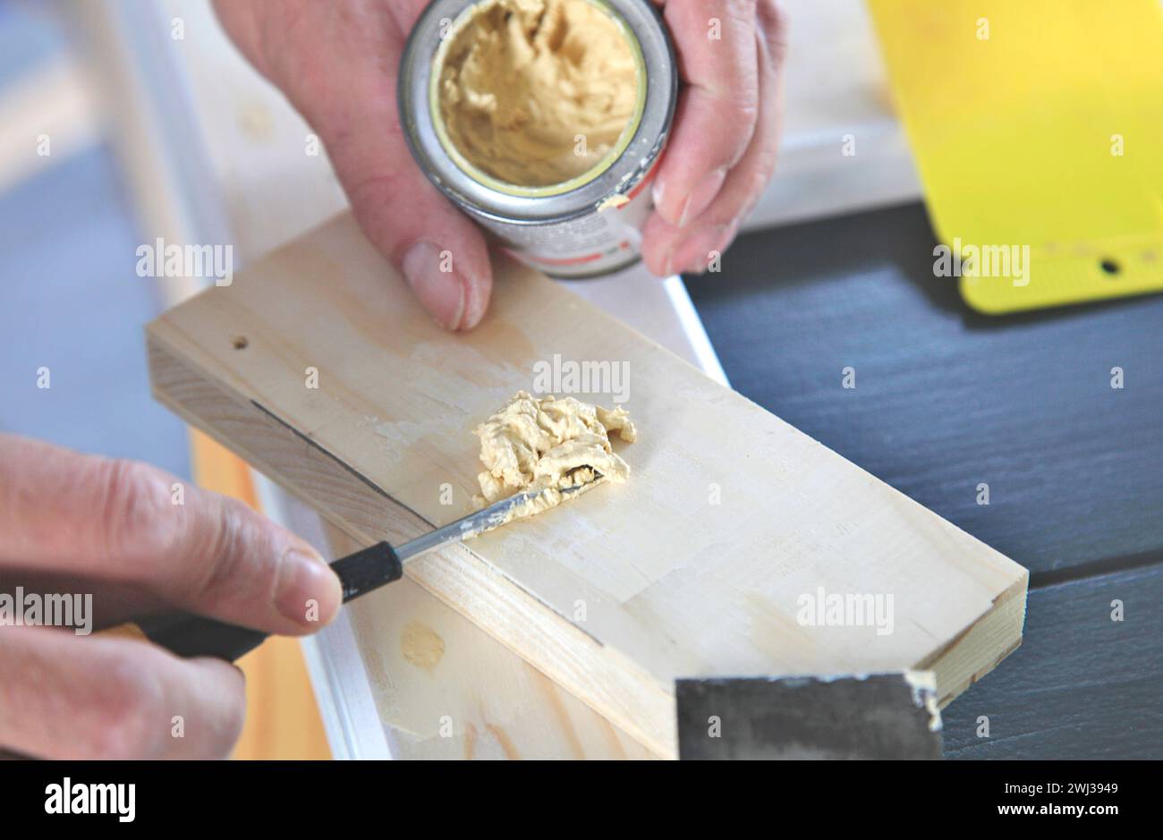 Woodwork. Close-up putty cans in man's hand. DIY worker applying filler ...