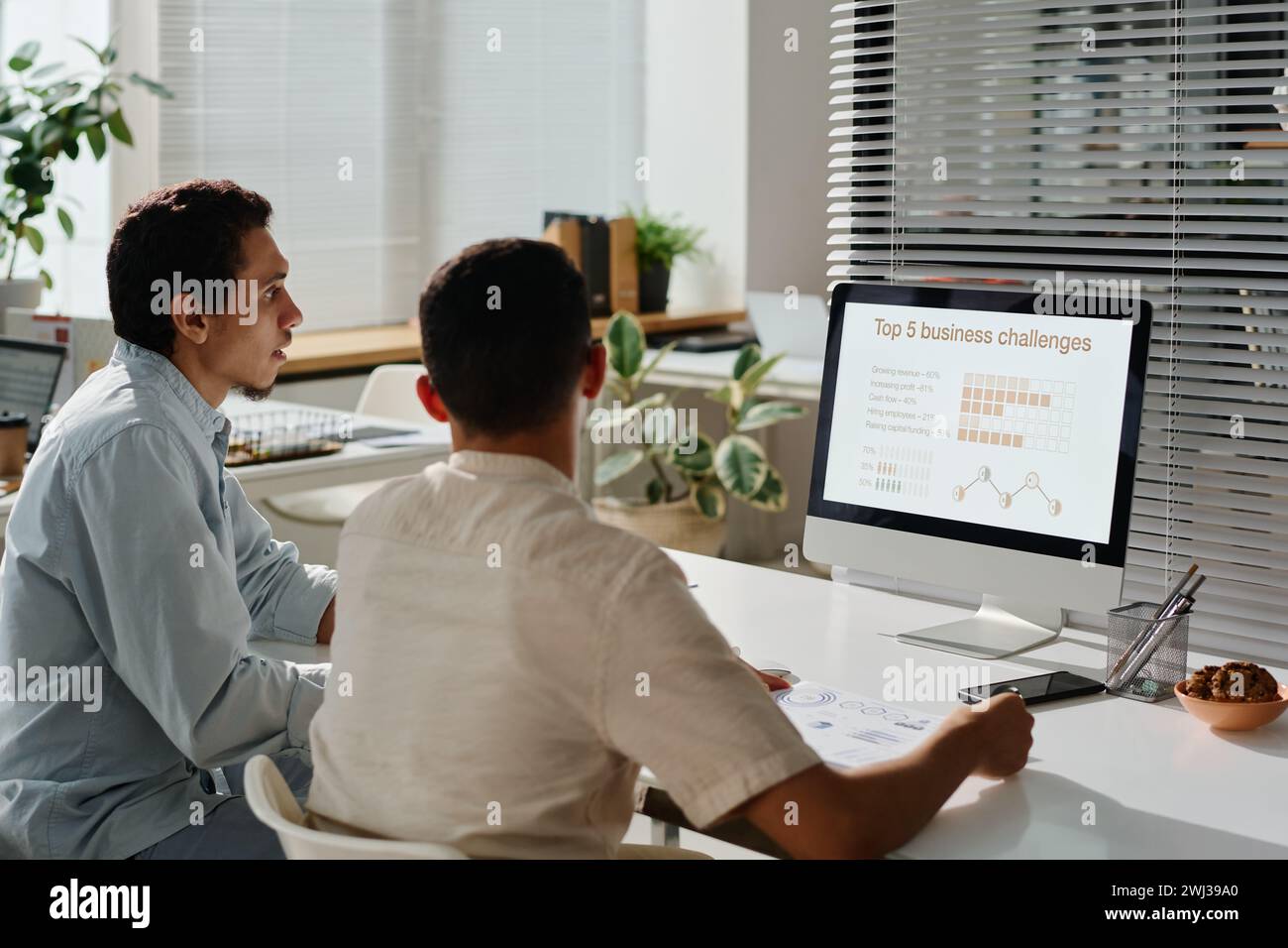 Two young male managers looking through online statistic data on screen ...