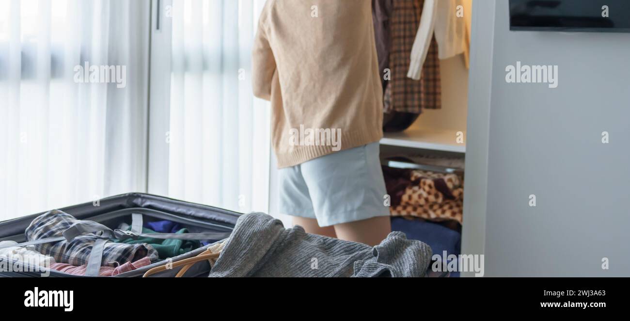 Asian girl preparing vacation choosing clothes with wardrobe in bedroom ...