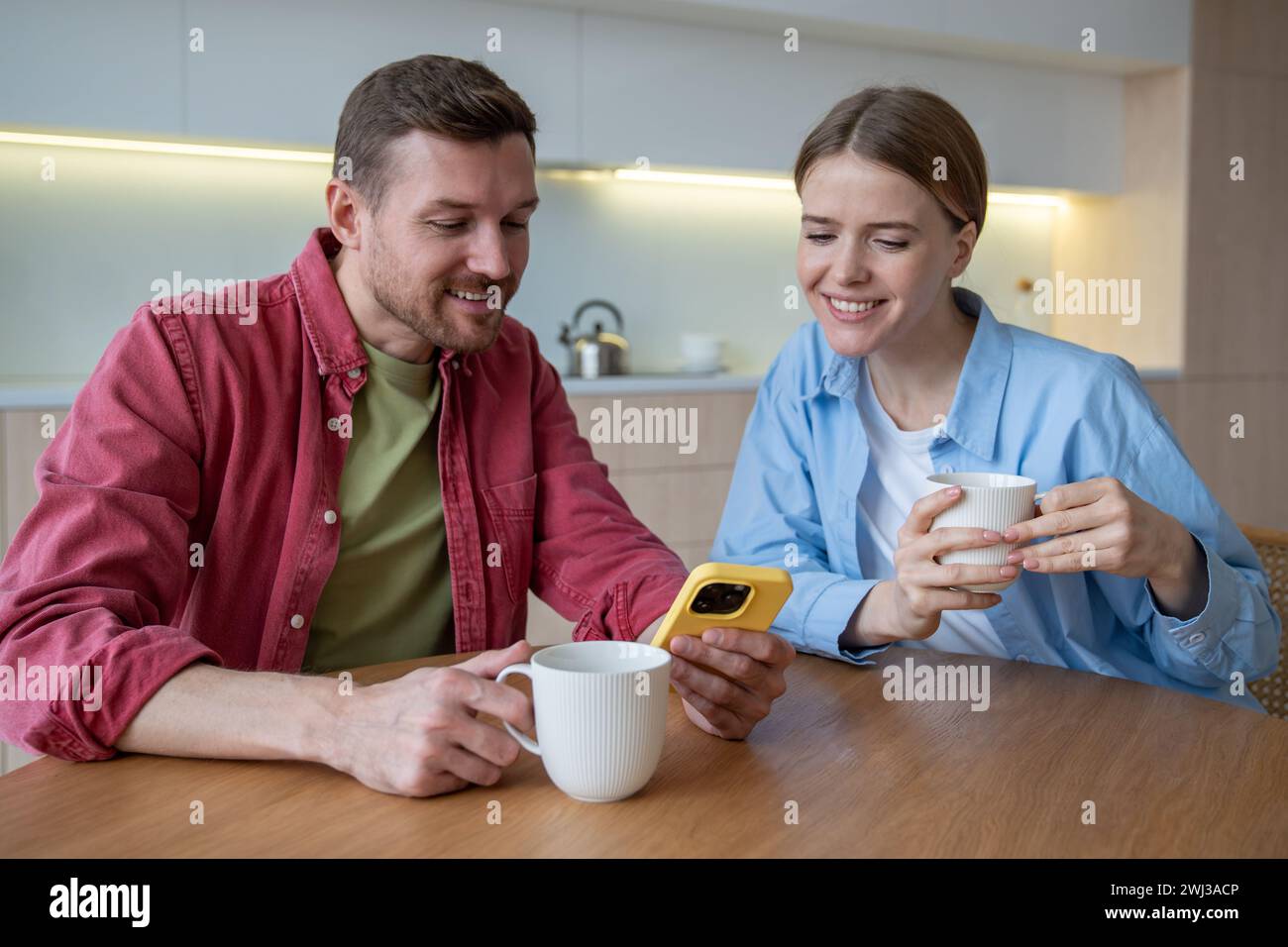 Loving married couple drinking tea, chatting, looking photos in ...