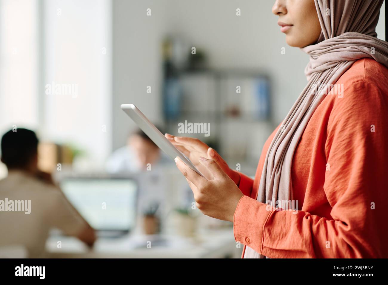 Cropped shot of young Muslim female manager using tablet while standing ...