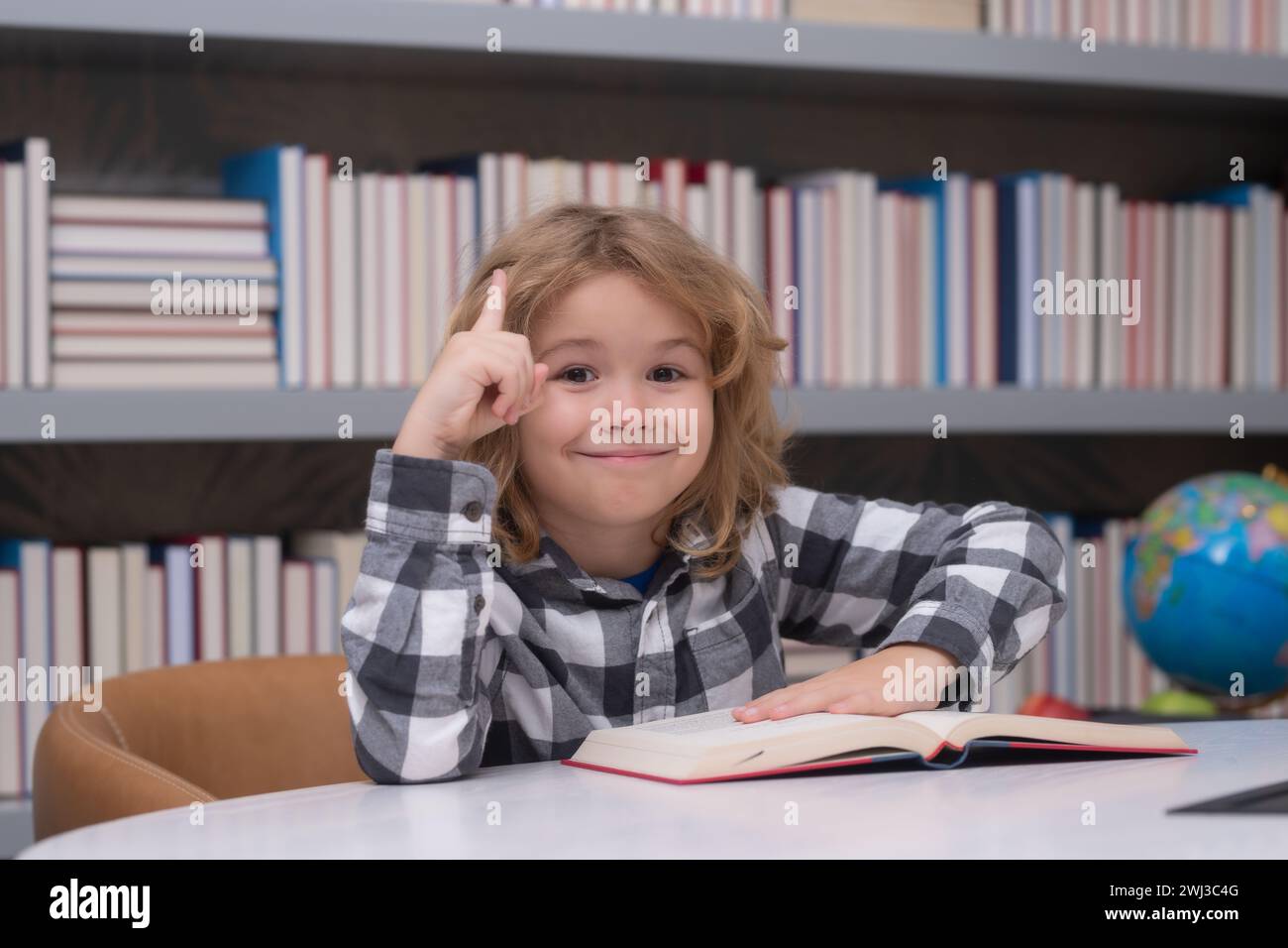 Portrait of school boy reading book in library. Kids development, learn ...