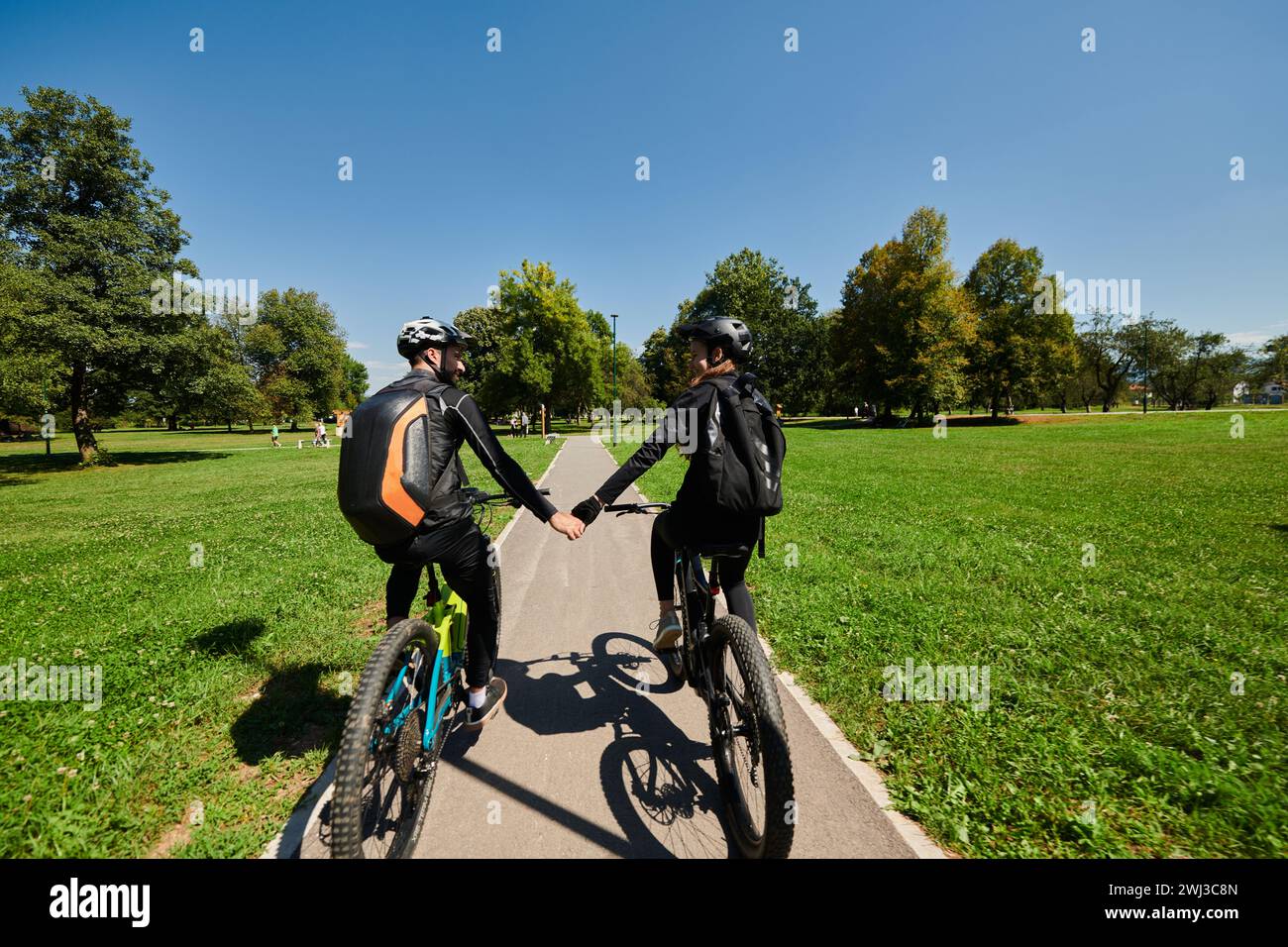 A sweet couple, adorned in cycling gear, rides their bicycles, their ...