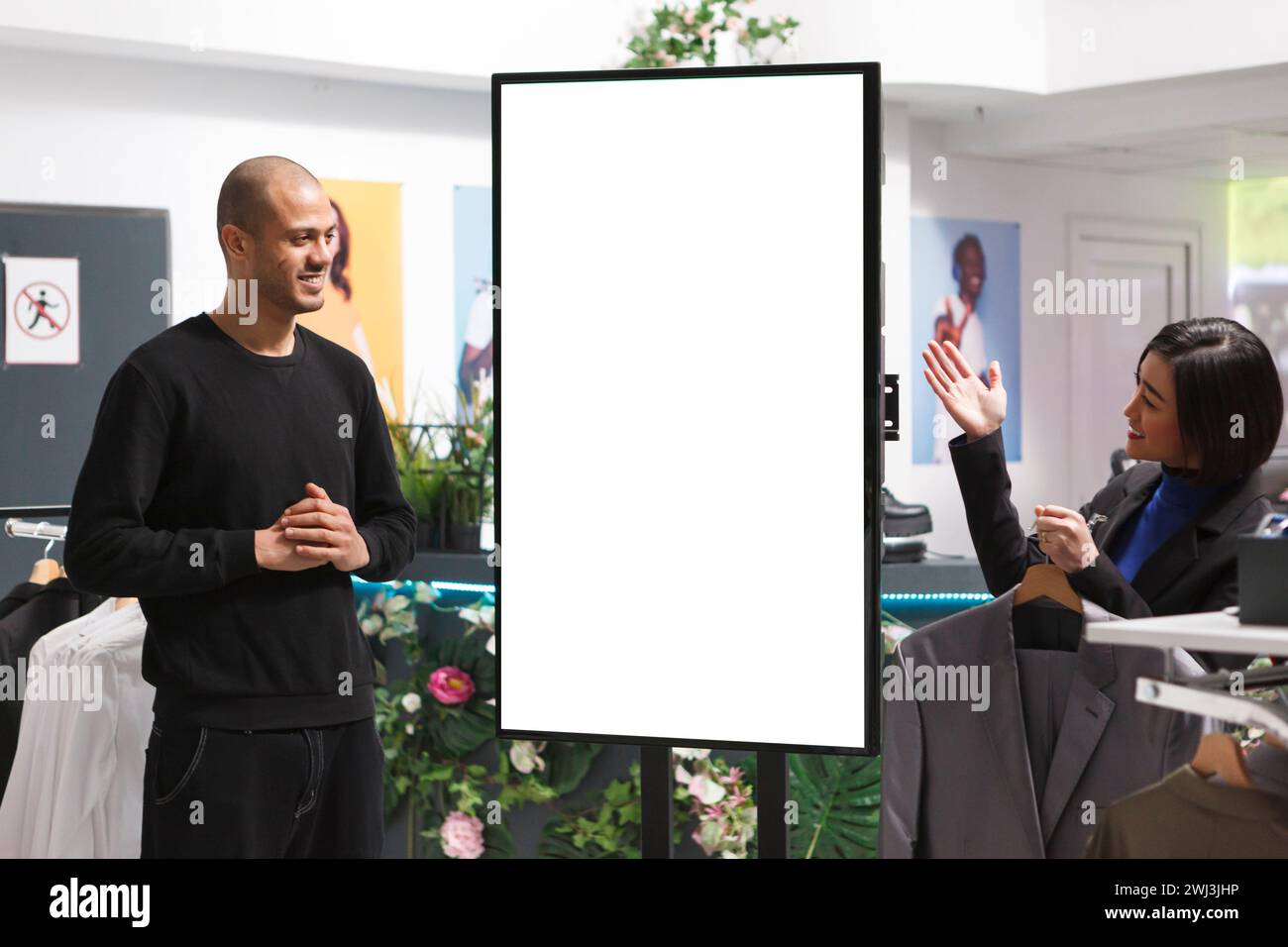 Clothing store smiling asian woman employee pointing at empty ...