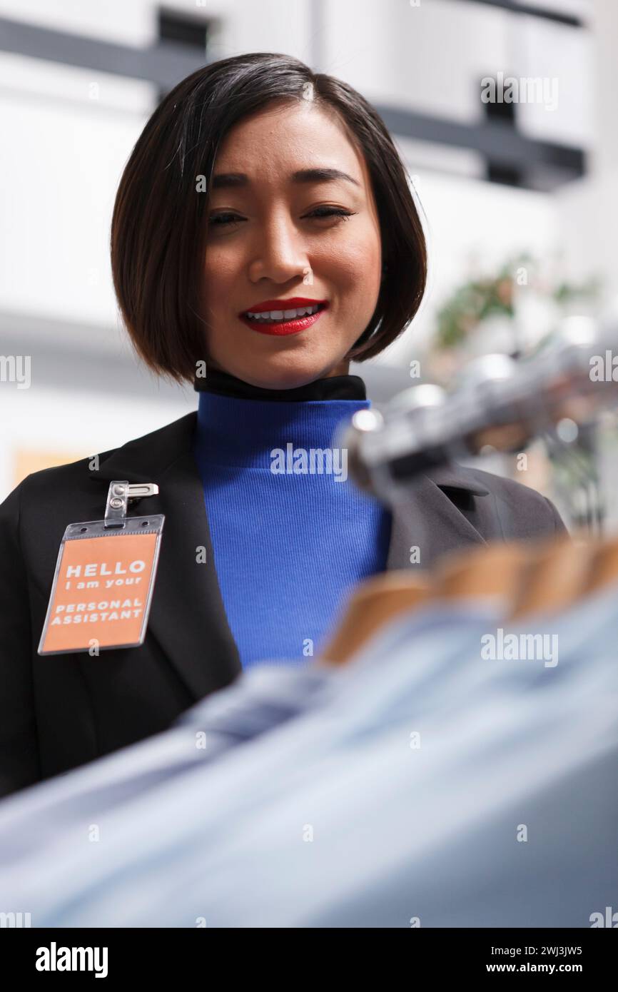 Fashion boutique smiling asian woman seller with badge examining formal ...