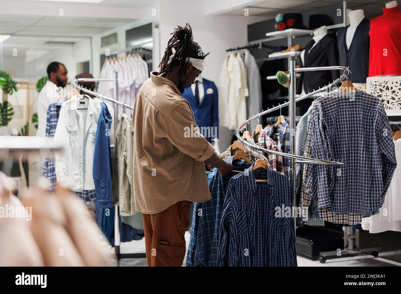 African american client looking at hanging shirts on rack in fashion ...