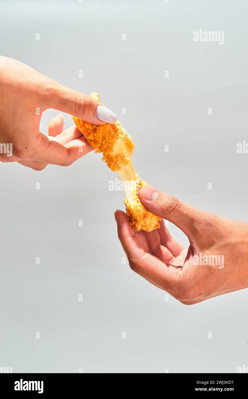 Crispy cheese fried breaded mozzarella cheese sticks stretch two hands ...