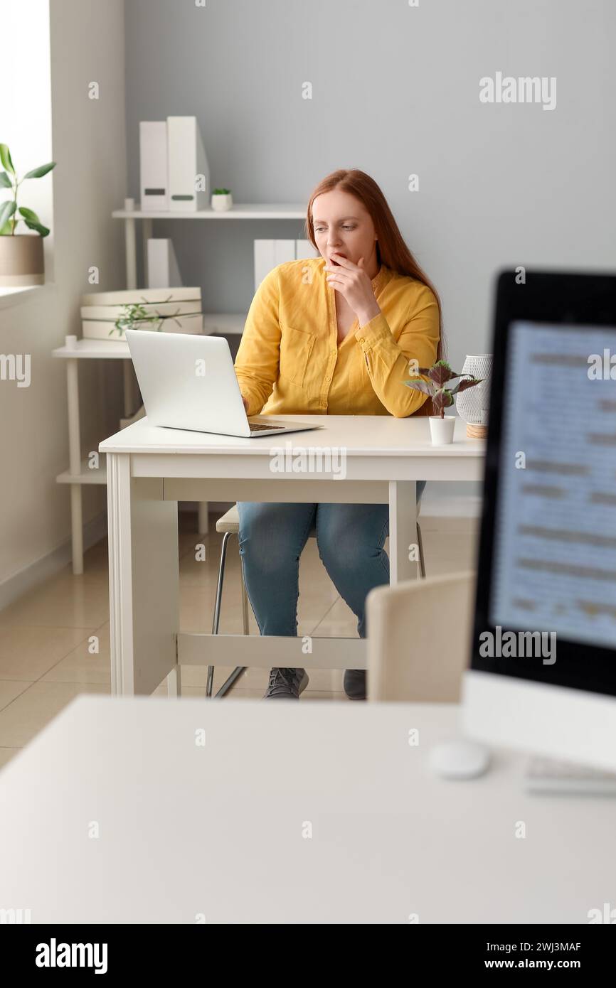 Tired female programmer working with laptop at table in office Stock ...