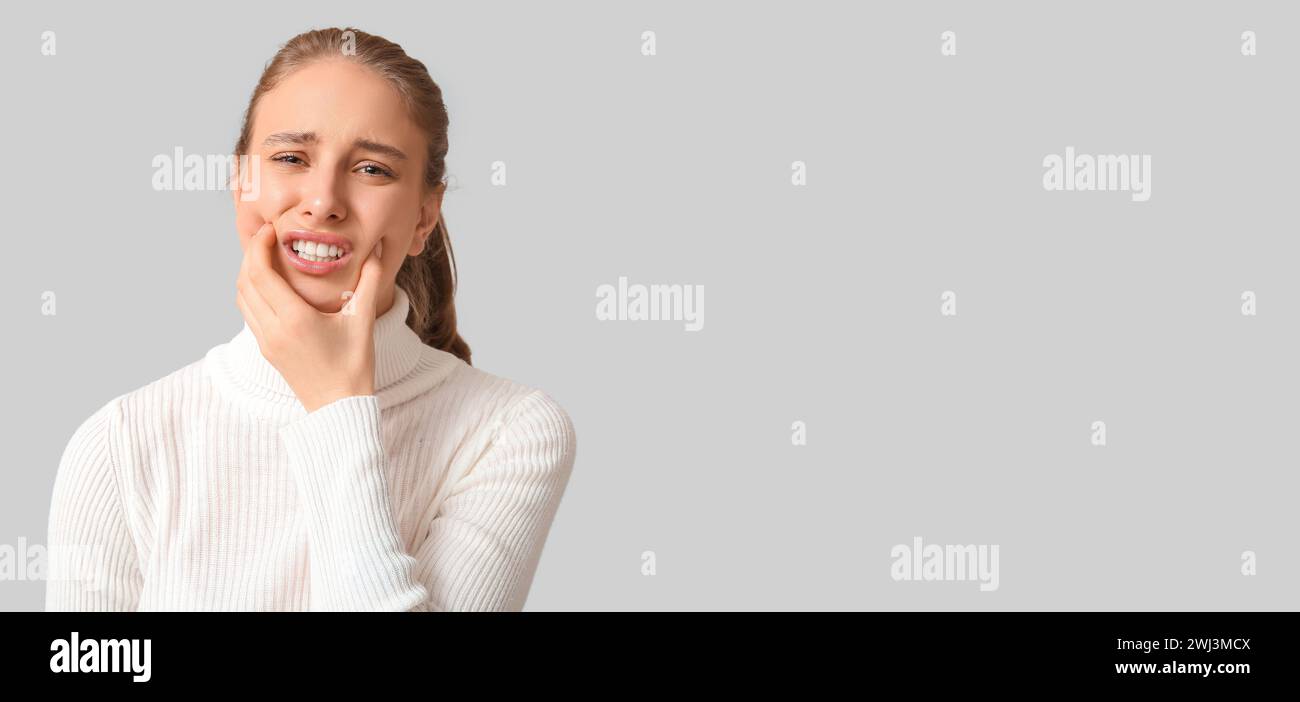 Young woman feeling tooth ache on light background with space for text ...