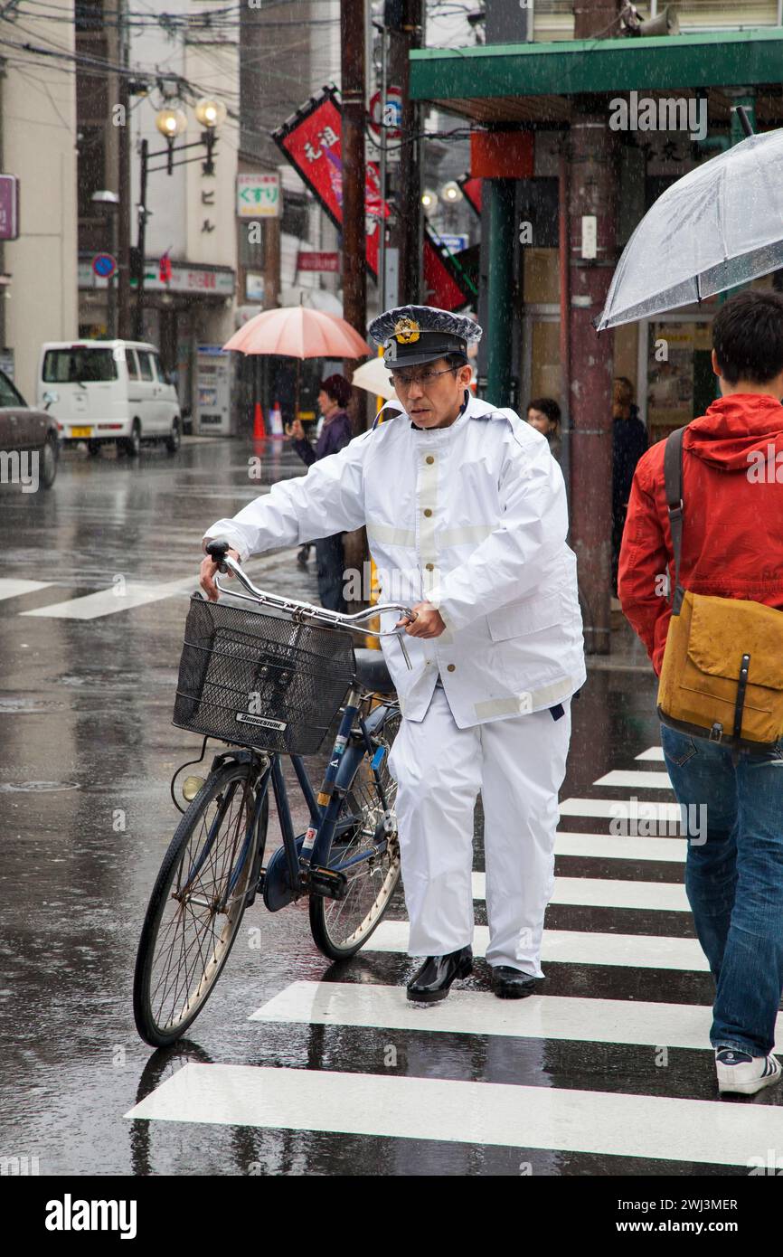 Policeman with bicycle crossing Shijo Street in downtown Gion, Kyoto ...
