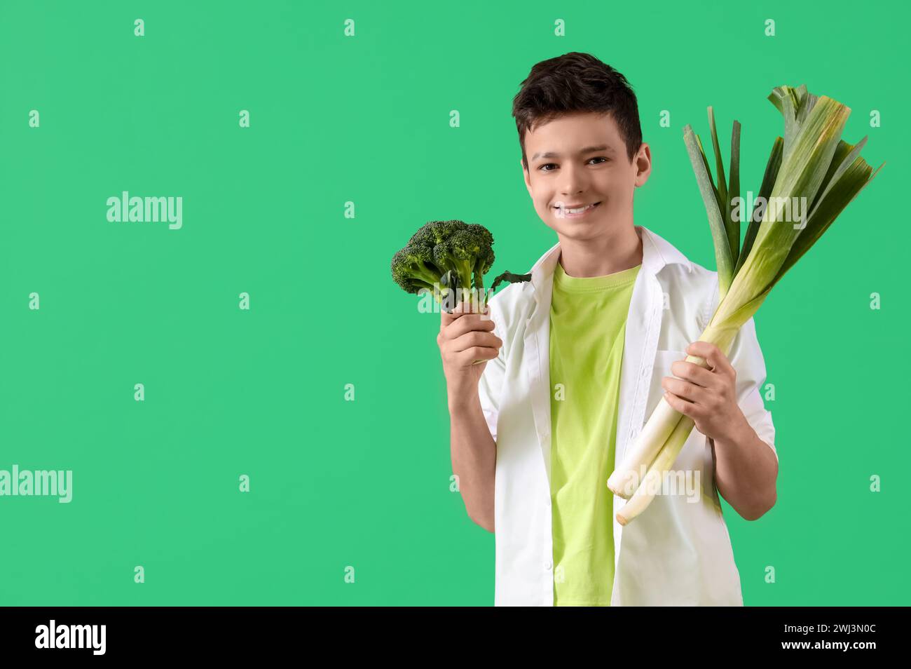 Cute little boy with broccoli and scallion on green background Stock ...