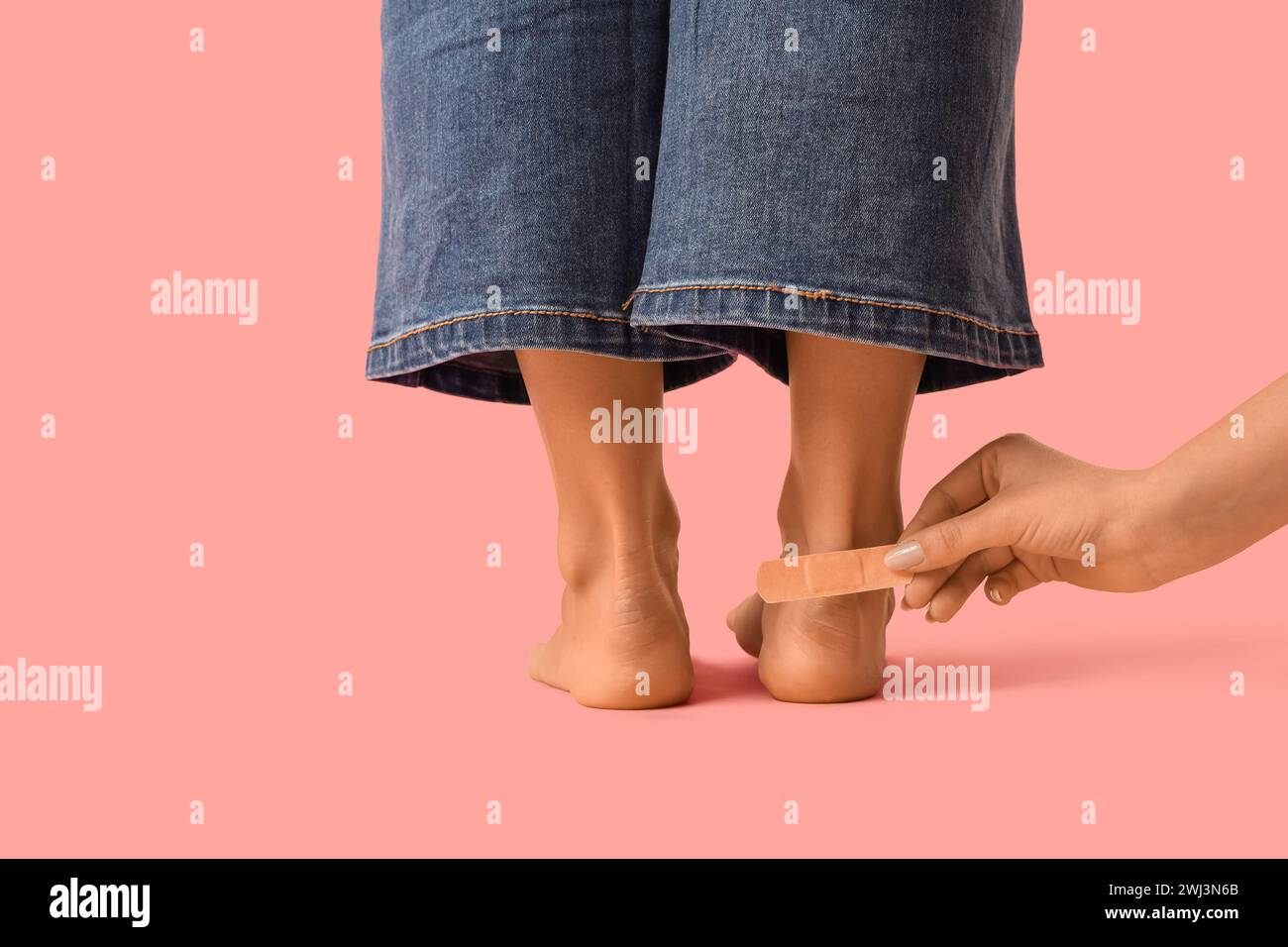 Female hand applying bandage to feet with callus on pink background ...