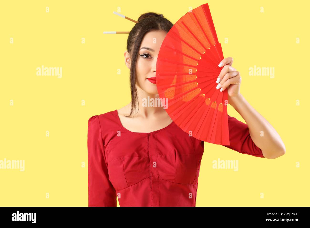 Young Asian woman with fan on yellow background. Chinese New Year ...