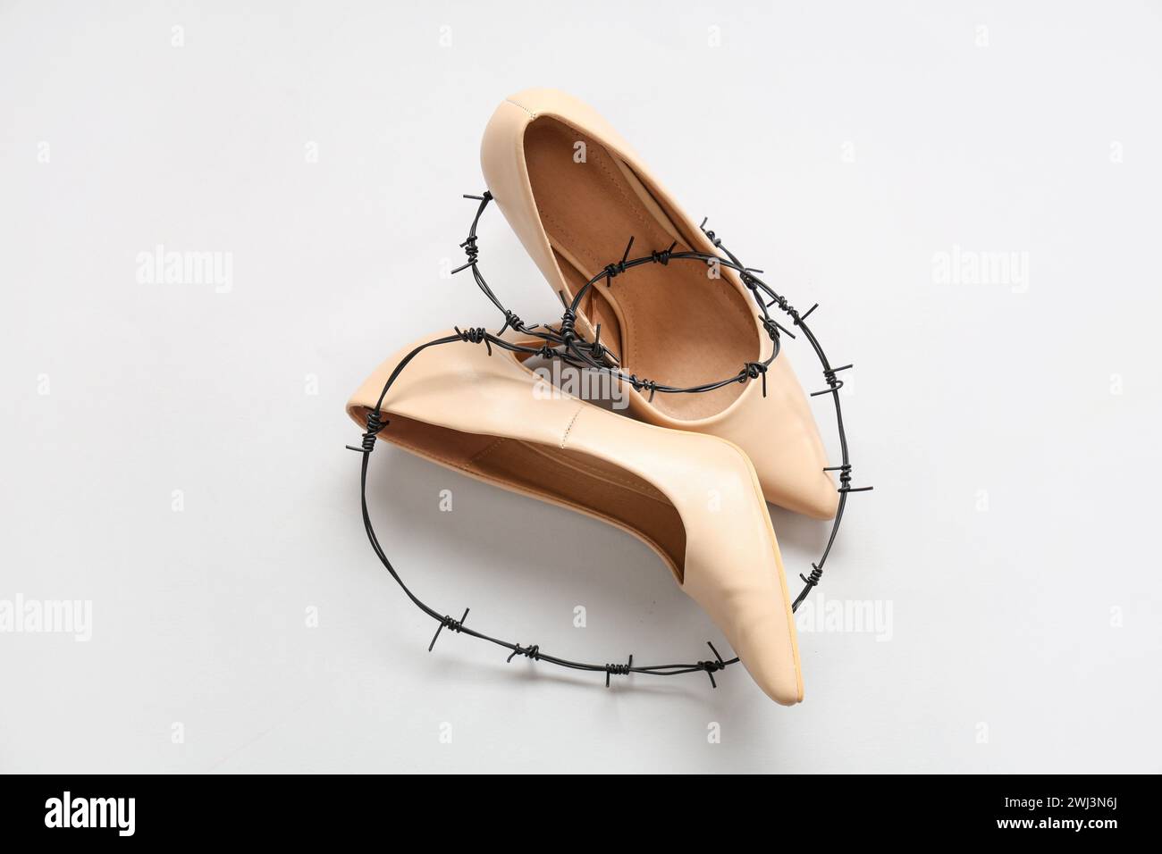 High-heeled shoes wrapped in barbed wire on white background ...