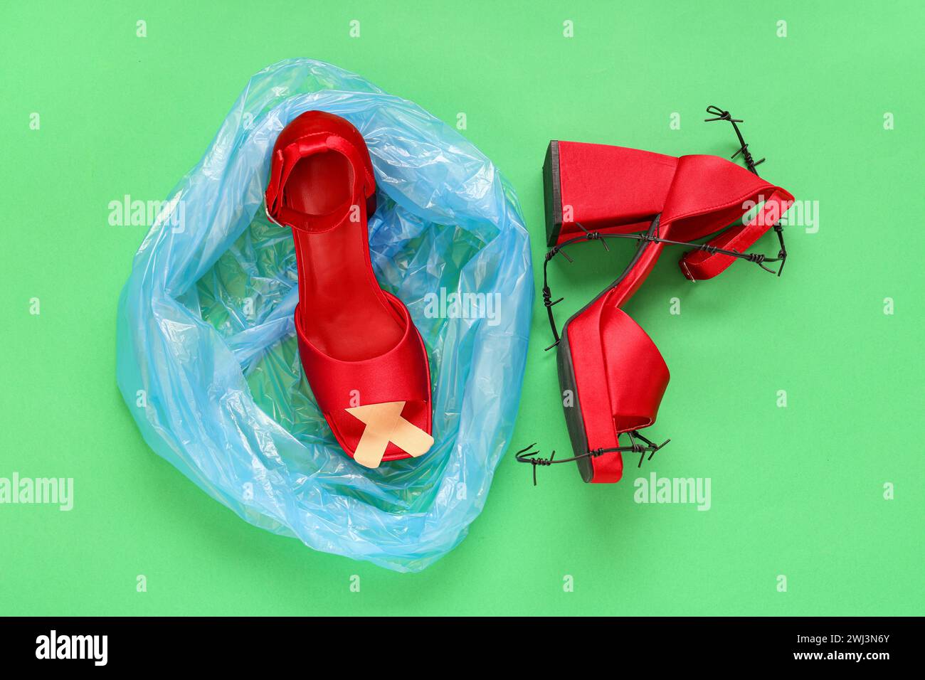 High-heeled shoes with plasters, barbed wire and garbage bag on green ...