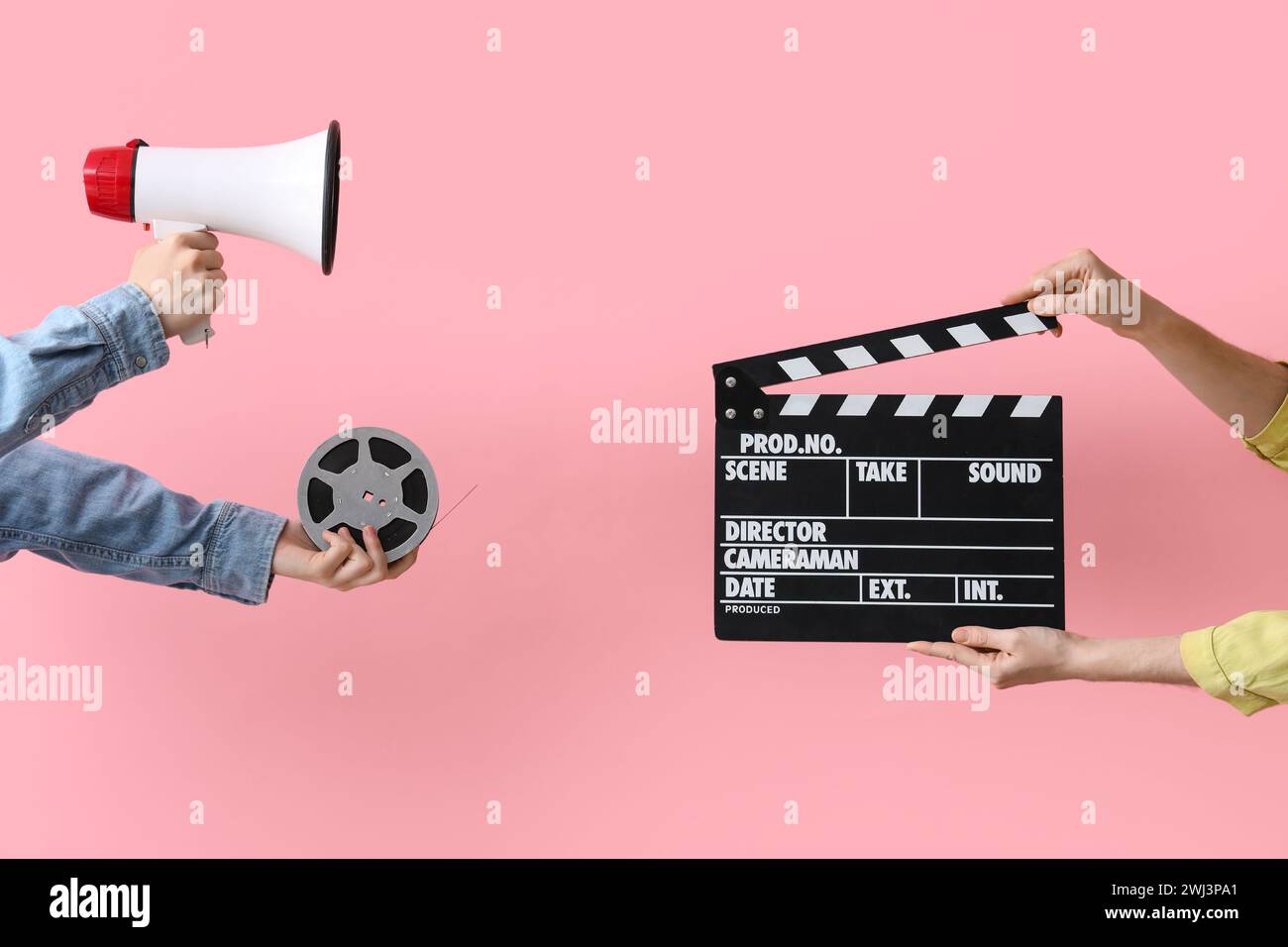 Hands with movie clapper, film reel and megaphone on pink background ...