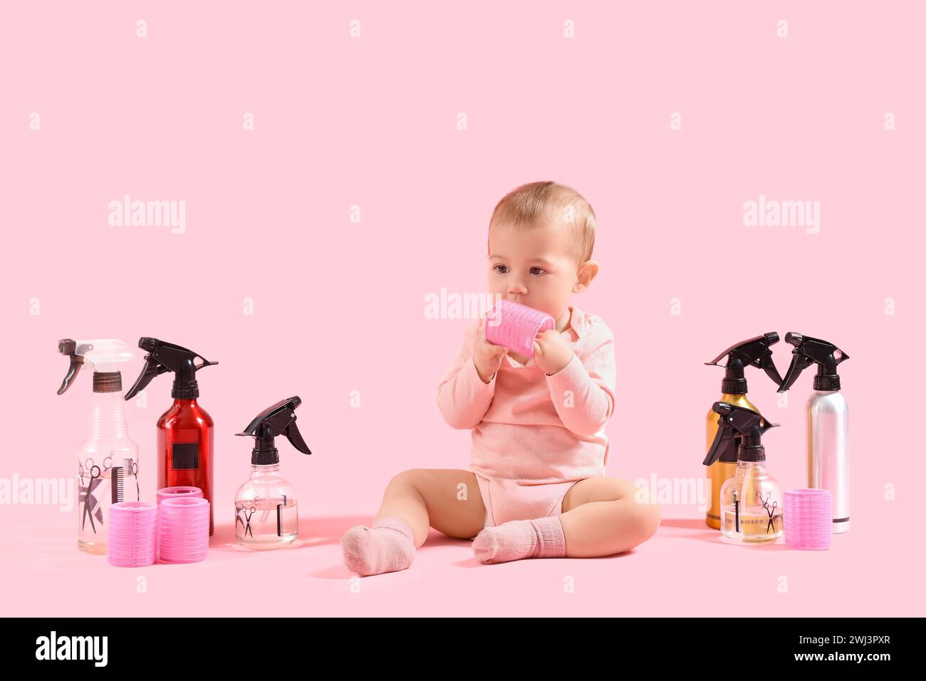 Cute baby hairdresser with curlers and sprays on pink background Stock ...
