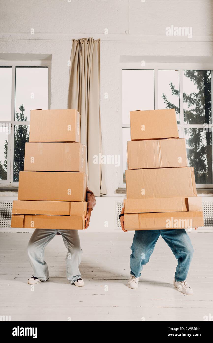 Happy young family couple man and woman moving carry heavy cardboard ...