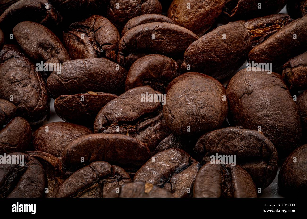 A close up of brown whole coffee beans with texture and dark color ...