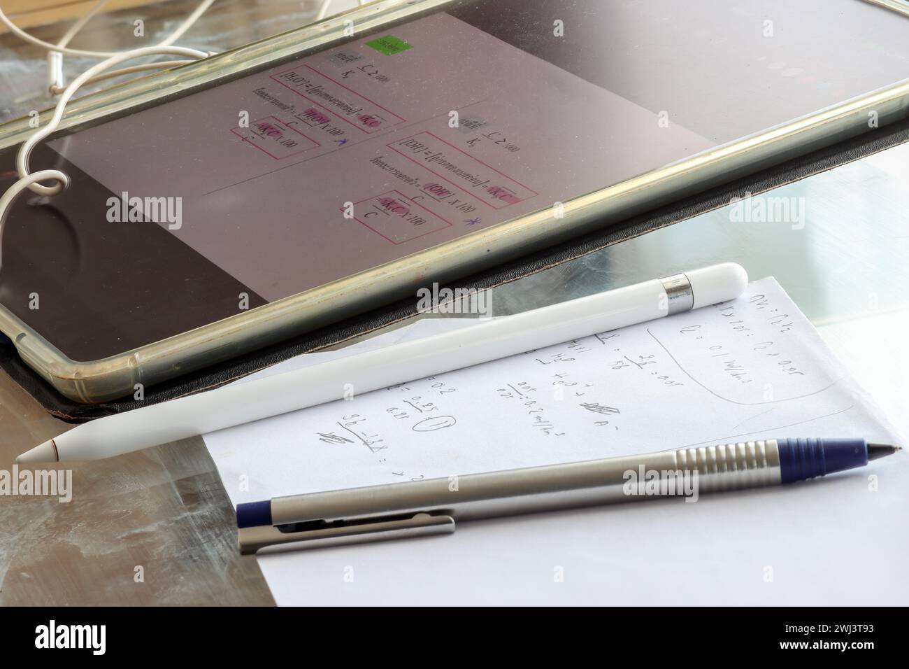 The paper and a tablet with chemical formulas and calculations on the ...