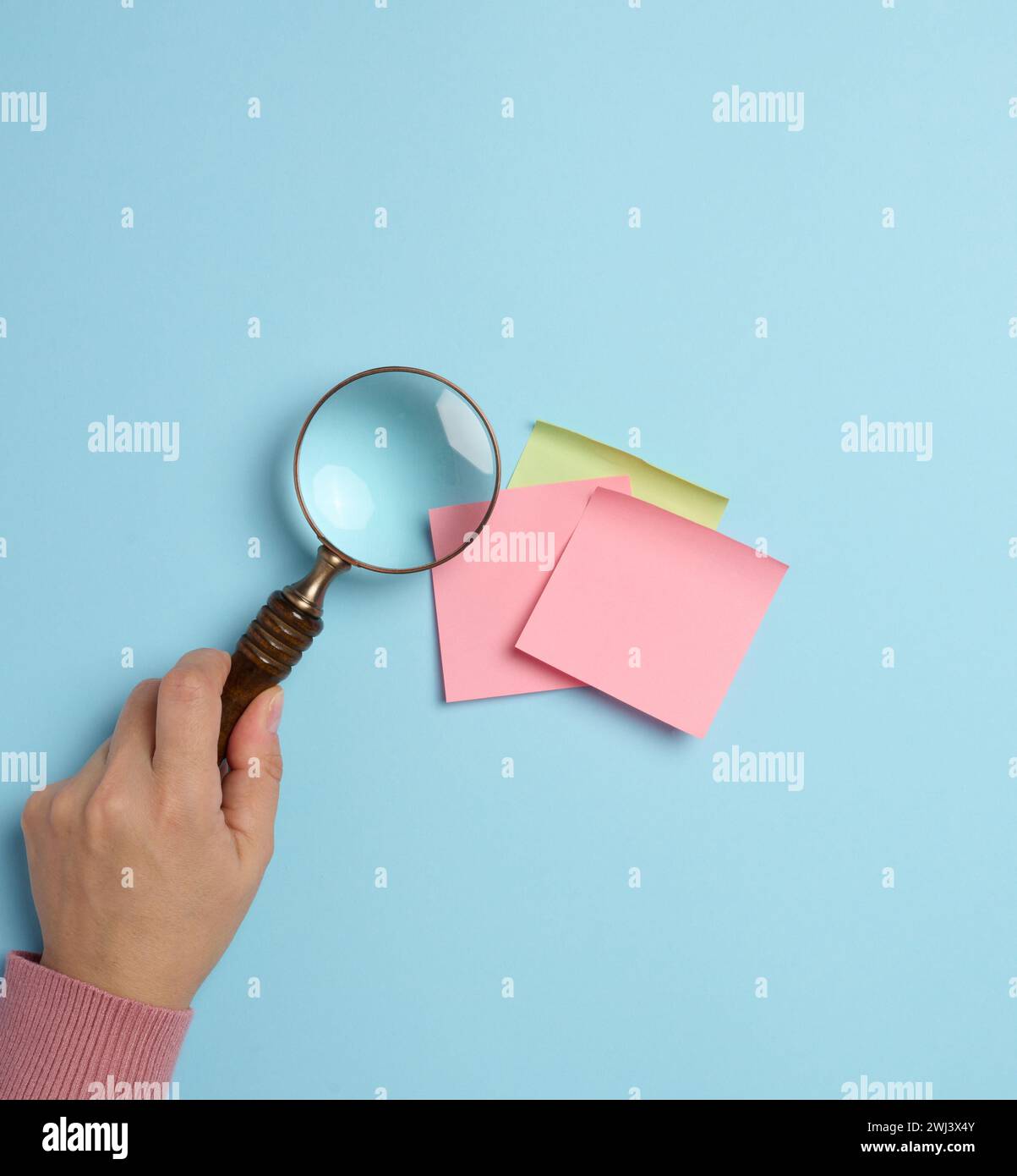 Empty paper stickers adhered to a blue background, and a female hand ...