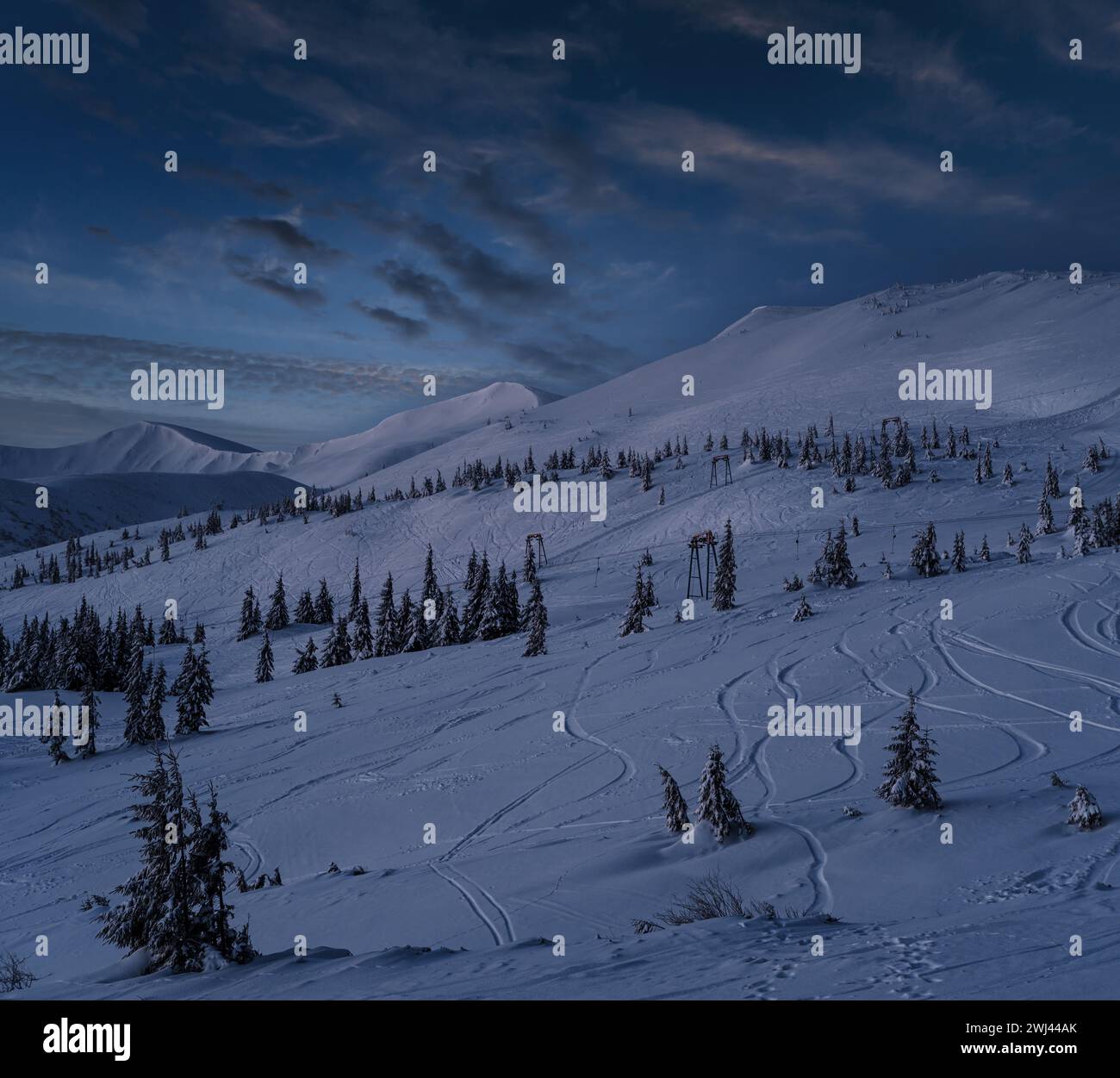 Alpine resort ski lift with seats going over the pre sunrise night ...